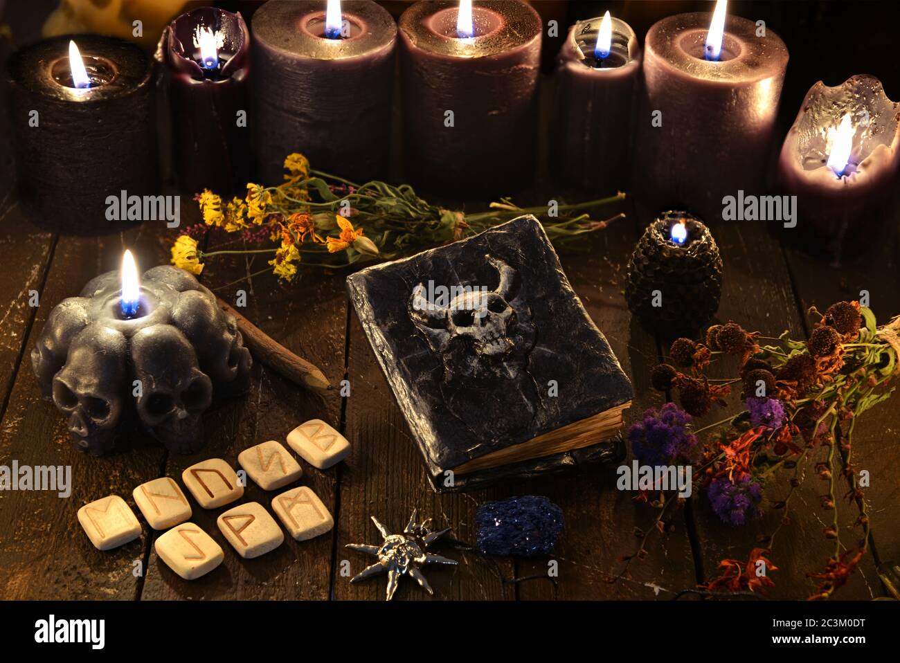 Black candles, runes, old witch book and herbs on wooden table. Wicca ...