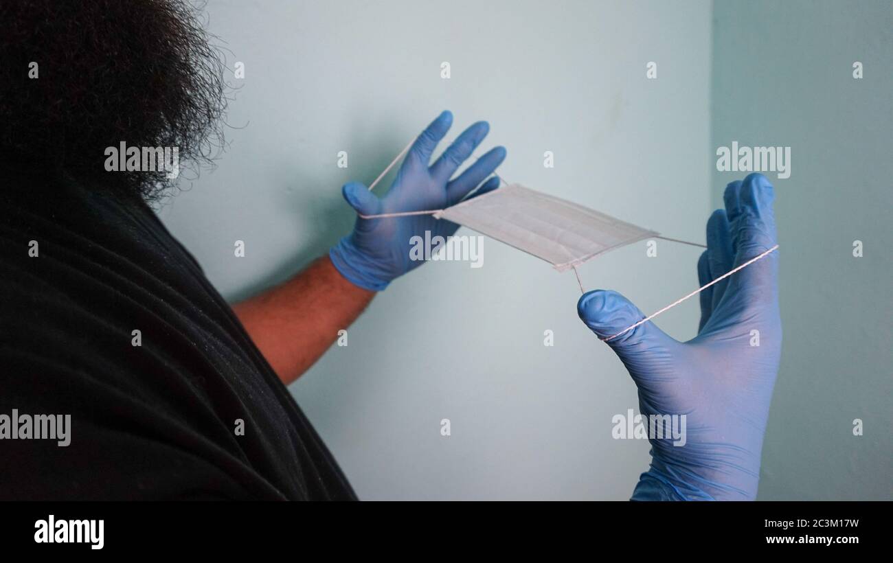 Bearded male wearing disposable gloves while stretching his facemask ...