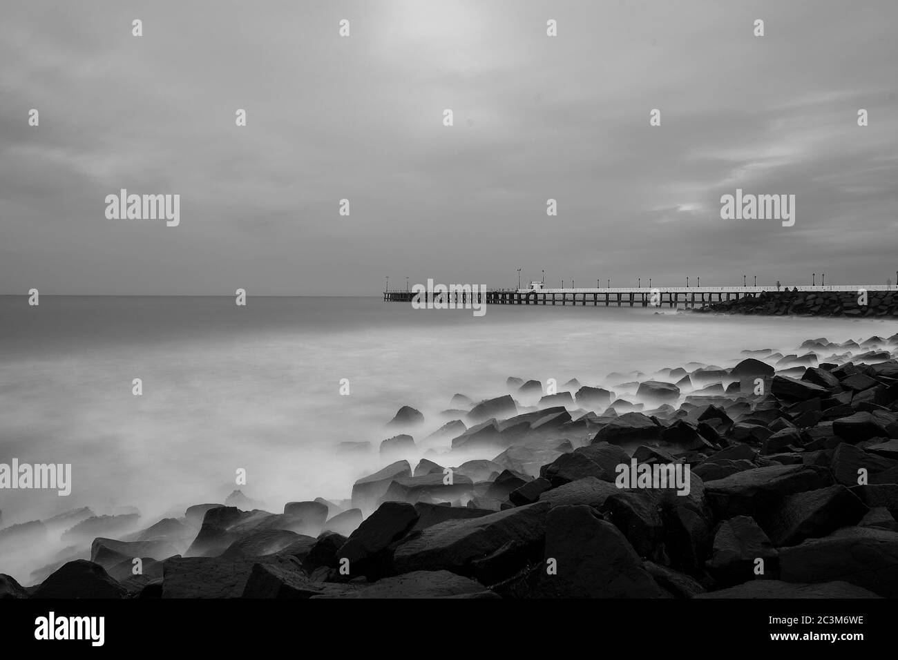 Grayscale shot of a rocky beach on a beautiful seascape background ...