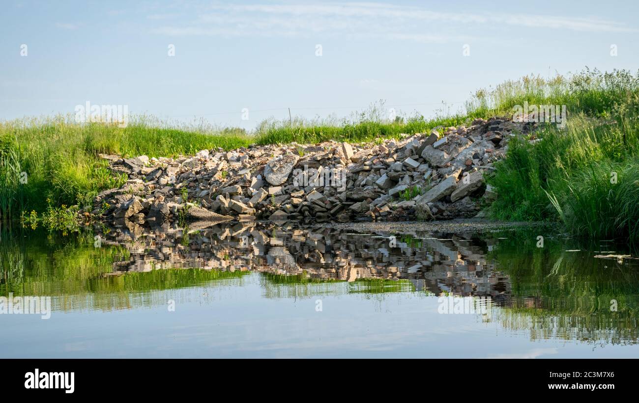 green summer landscape, river bank pollution, concrete blocks thrown ...