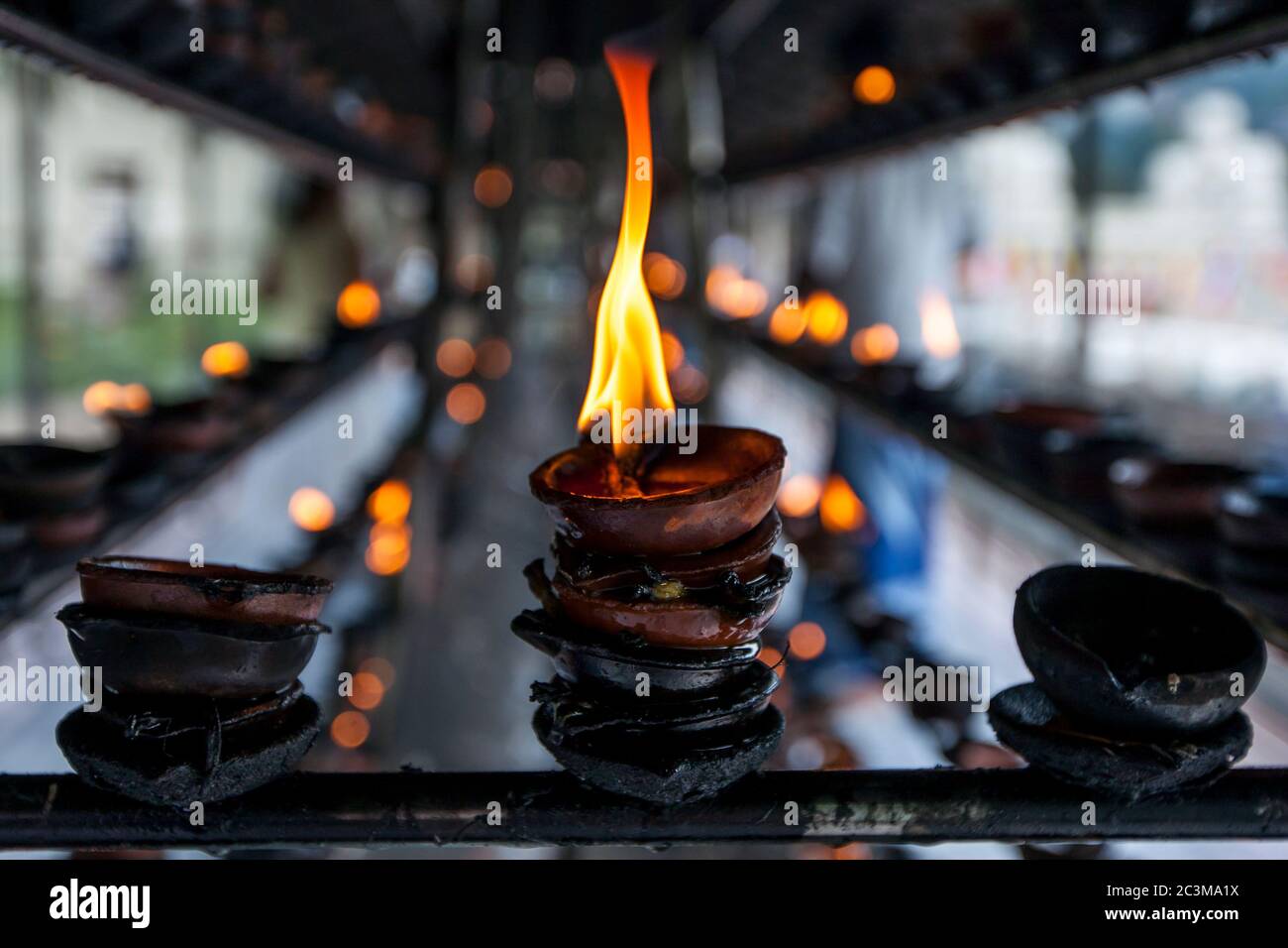 A flame burns in an oil cup at the Buddhist Temple of the Sacred Tooth ...