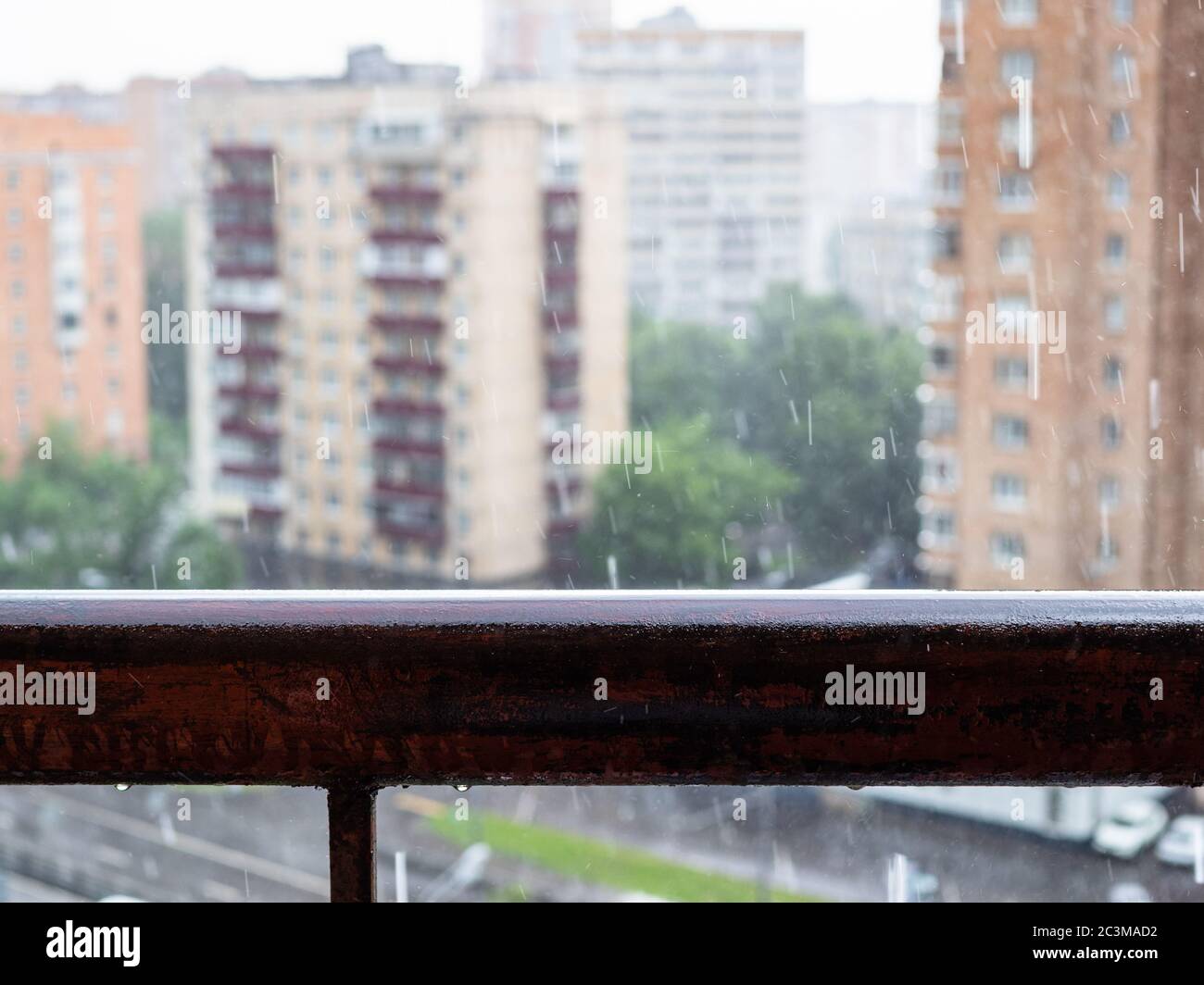 wet balcony railing and view of blurred residential district on ...