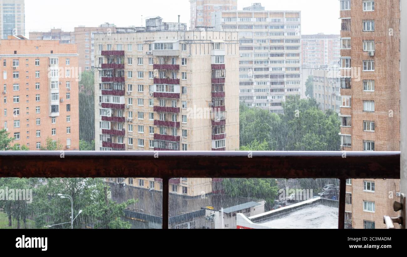 panoramic view of wet balcony railing and residential district in rain ...