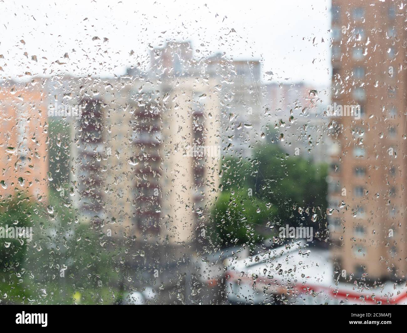 raindrops on window glass and view of blurred apartment houses on ...