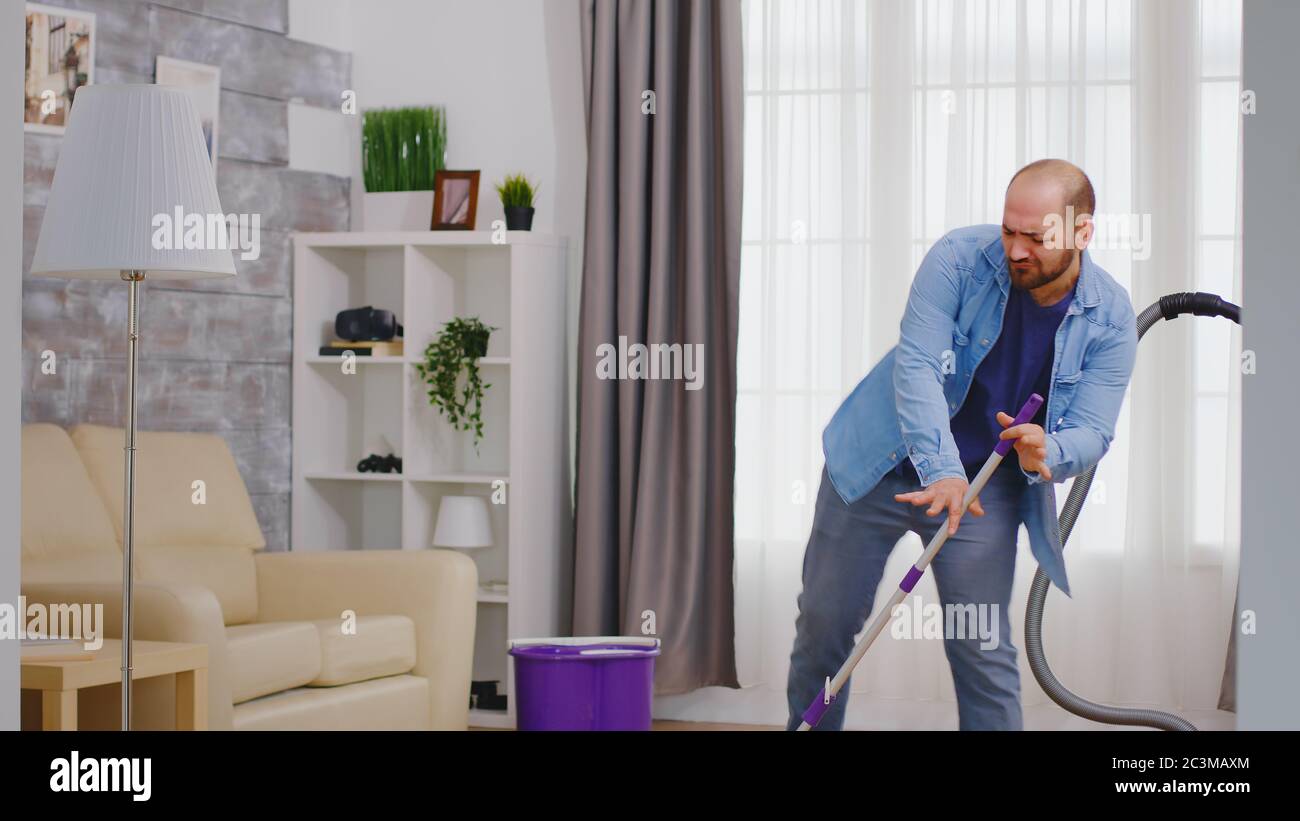 Cheerful man having fun while cleaning the house using modern mop Stock ...