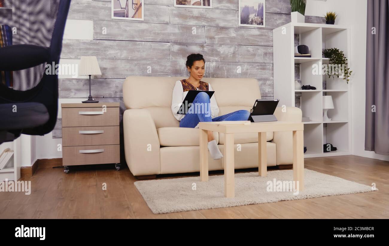 Woman taking notes on clipboard during a video call while working from ...