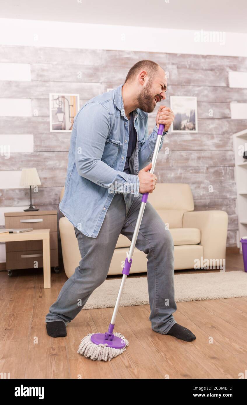 Joyful man singing and cleaning the house Stock Photo - Alamy