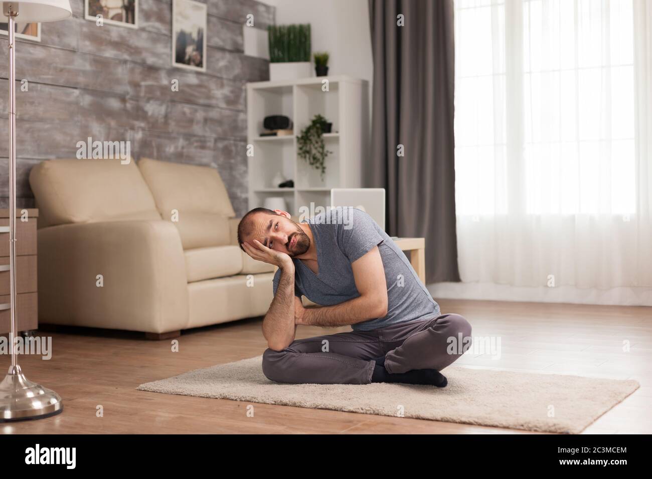 Anxious man on carpet in living room during self isolation Stock Photo ...