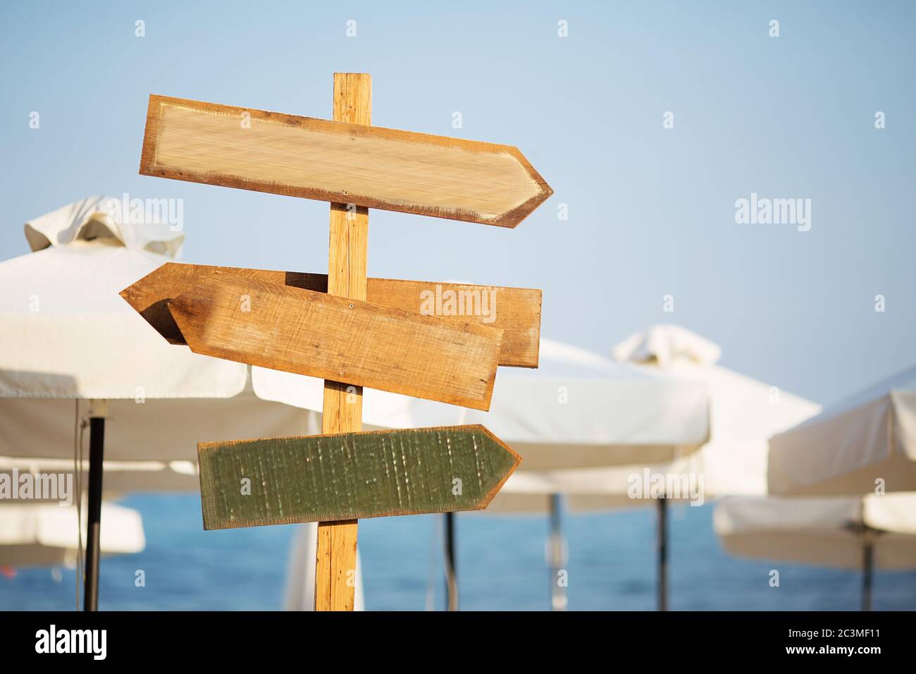 Wooden pointer post with copy space at the beach. arrows on a guidepost ...