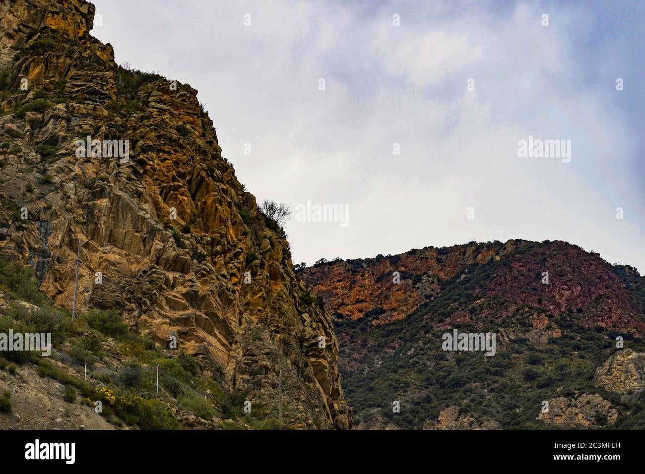 Landscape of rocks covered in greenery under a cloudy sky at daytime ...