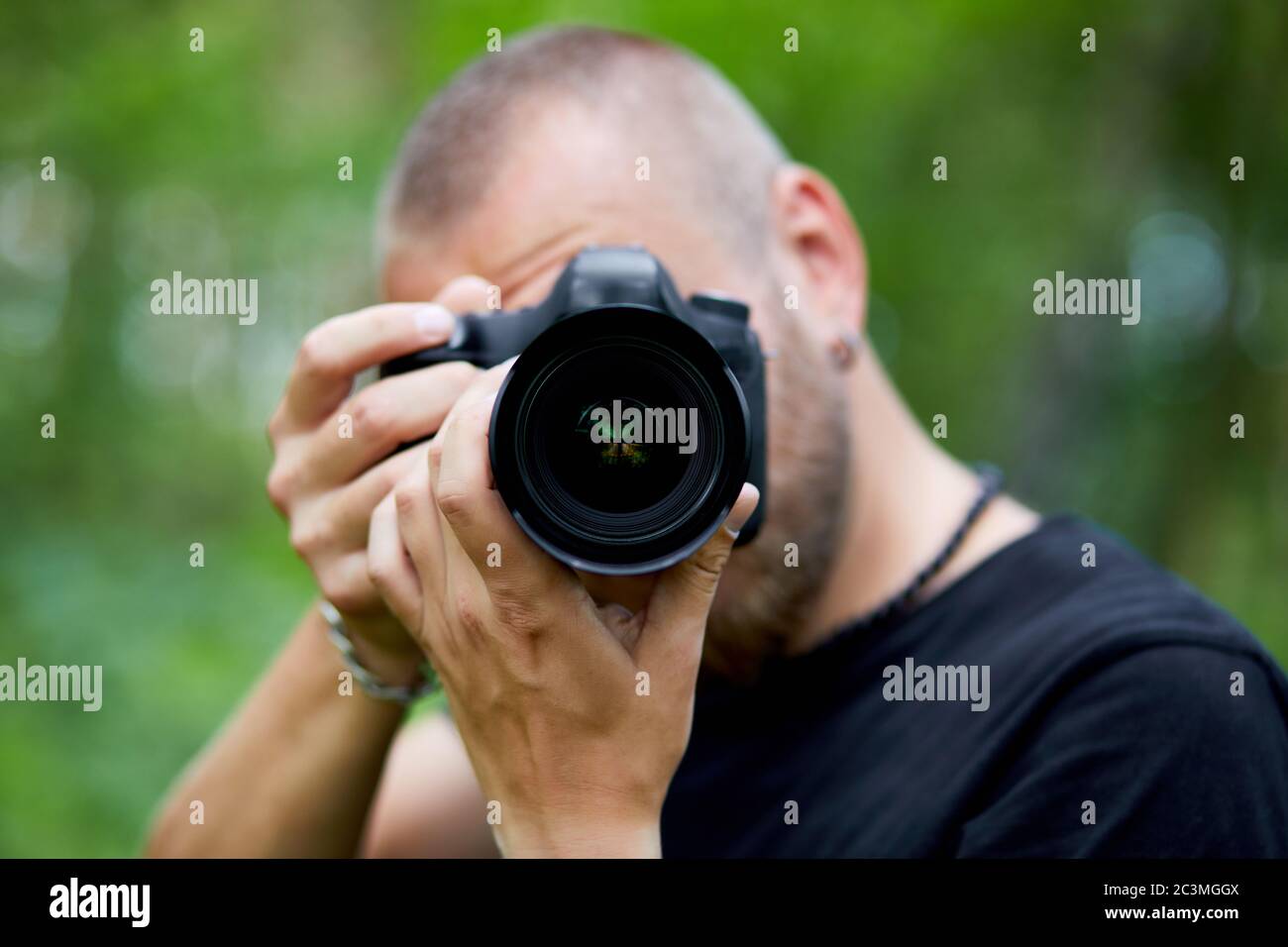 Portrait of a male photographer covering her face with the camera ...