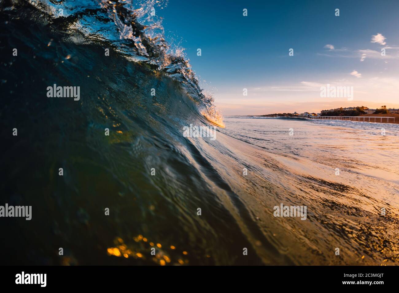 Barrel wave in ocean with sunrise tones and beach at background Stock ...