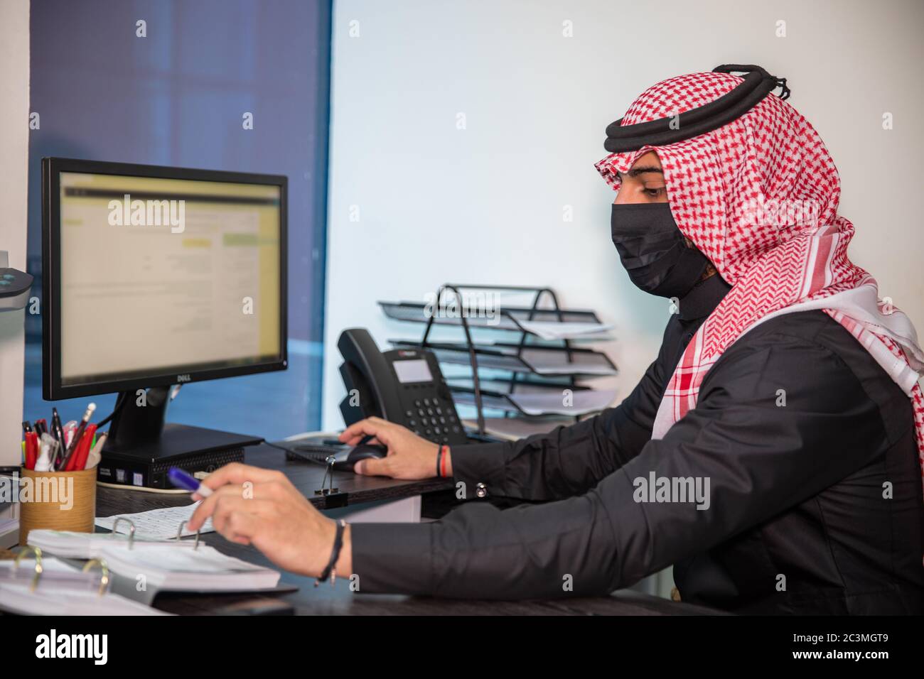 A Saudi man wears a mask and works from the office on the first working ...
