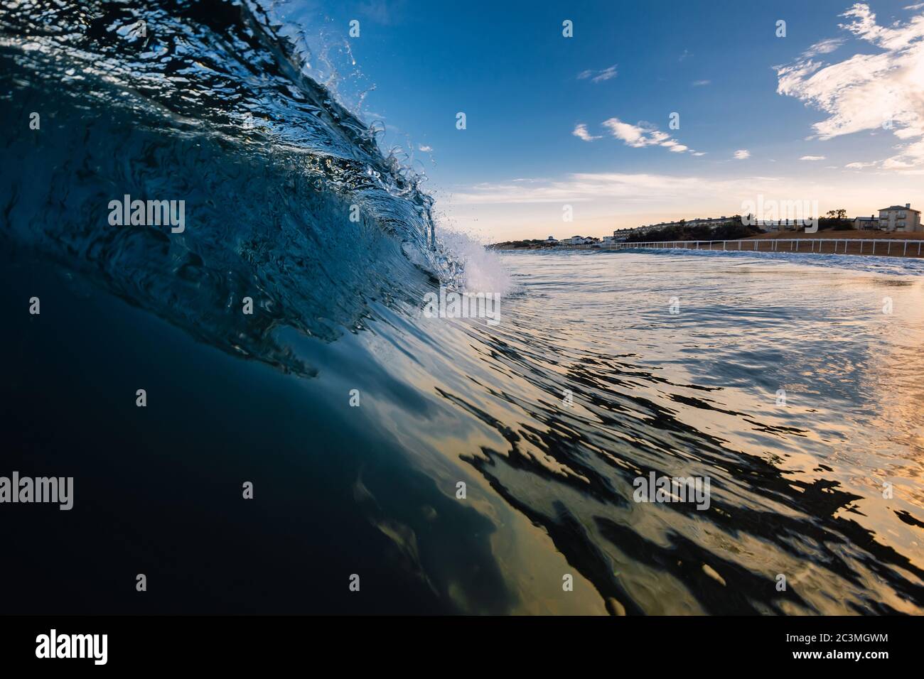 Barrel wave in ocean with sunrise tones and beach at background Stock ...