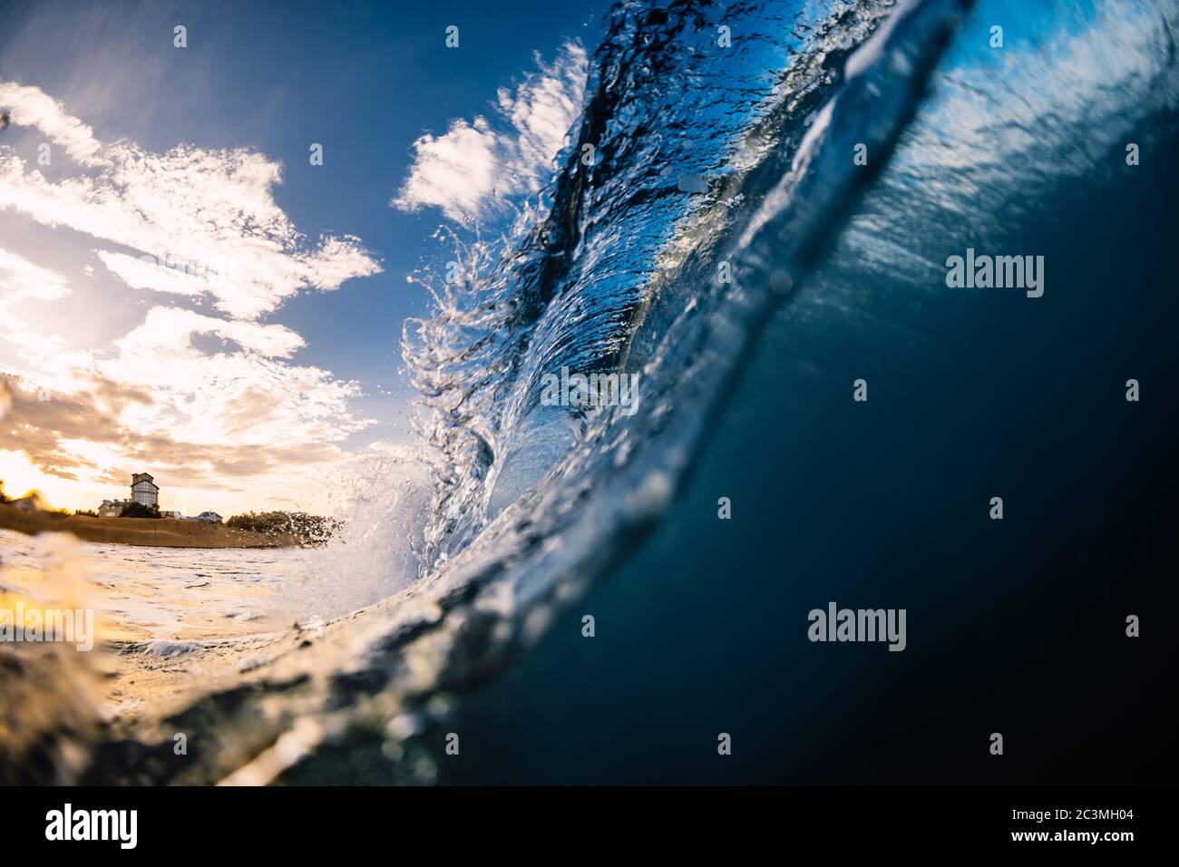 Barrel wave in ocean with sunrise tones and beach at background Stock ...