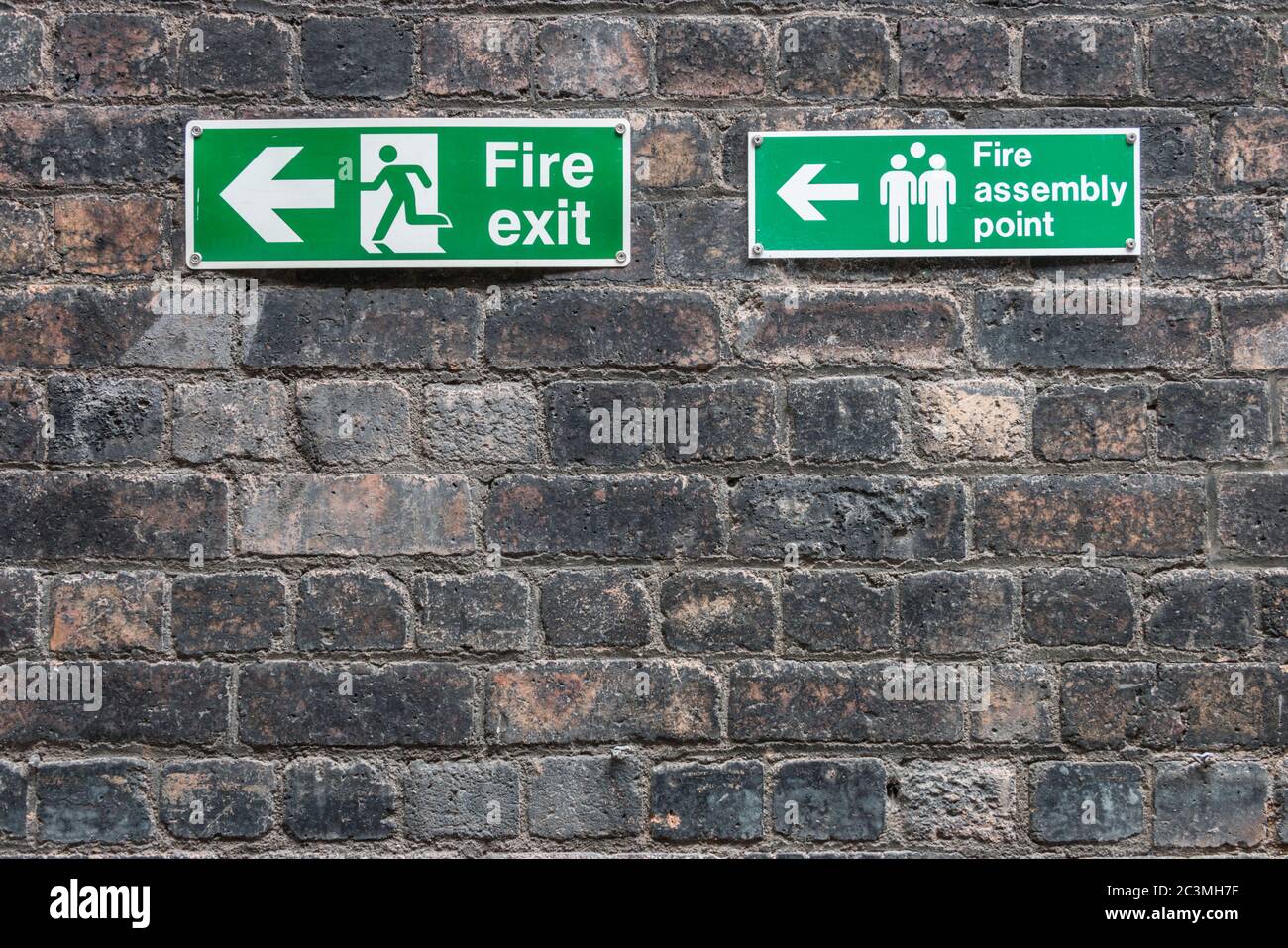 fire exit fire assembly signs on old brick wall at Middleport Pottery ...