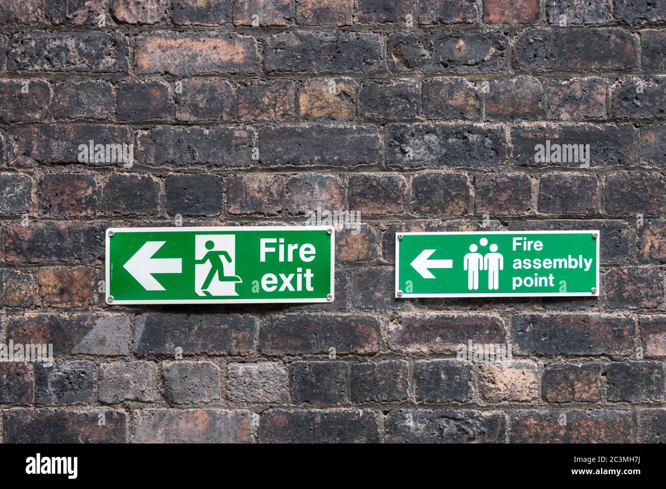 fire exit fire assembly signs on old brick wall at Middleport Pottery ...