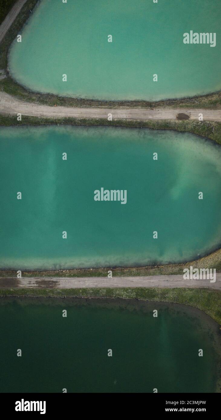 Overhead shot of lakes separated by narrow roads on land Stock Photo ...