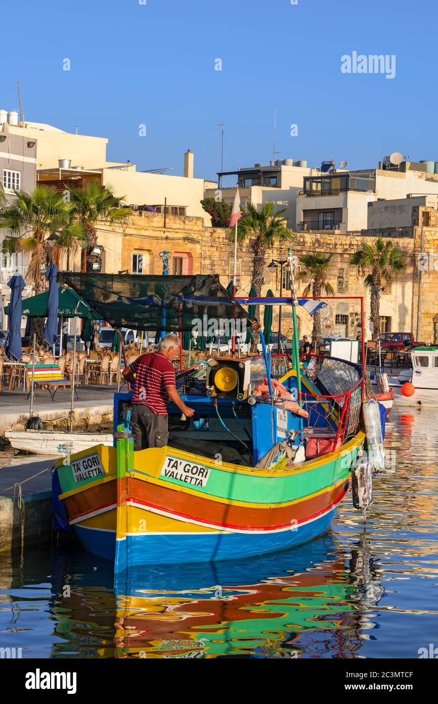 Fisherman on a traditional Luzzu boat in port of Marsaxlokk fishing ...