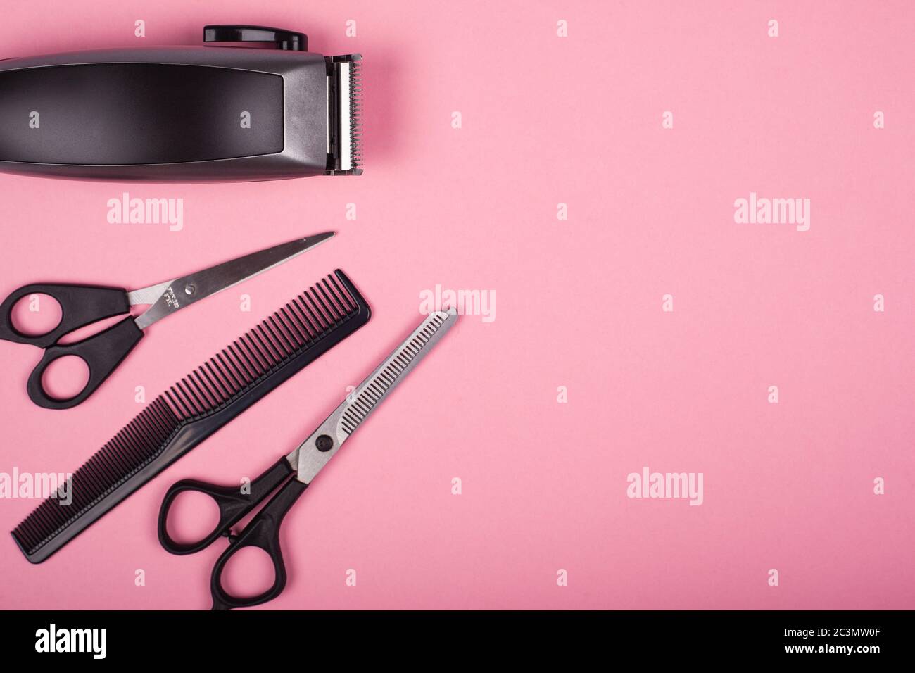 hairdressing hair cutting tools on a pink background top view, copy ...