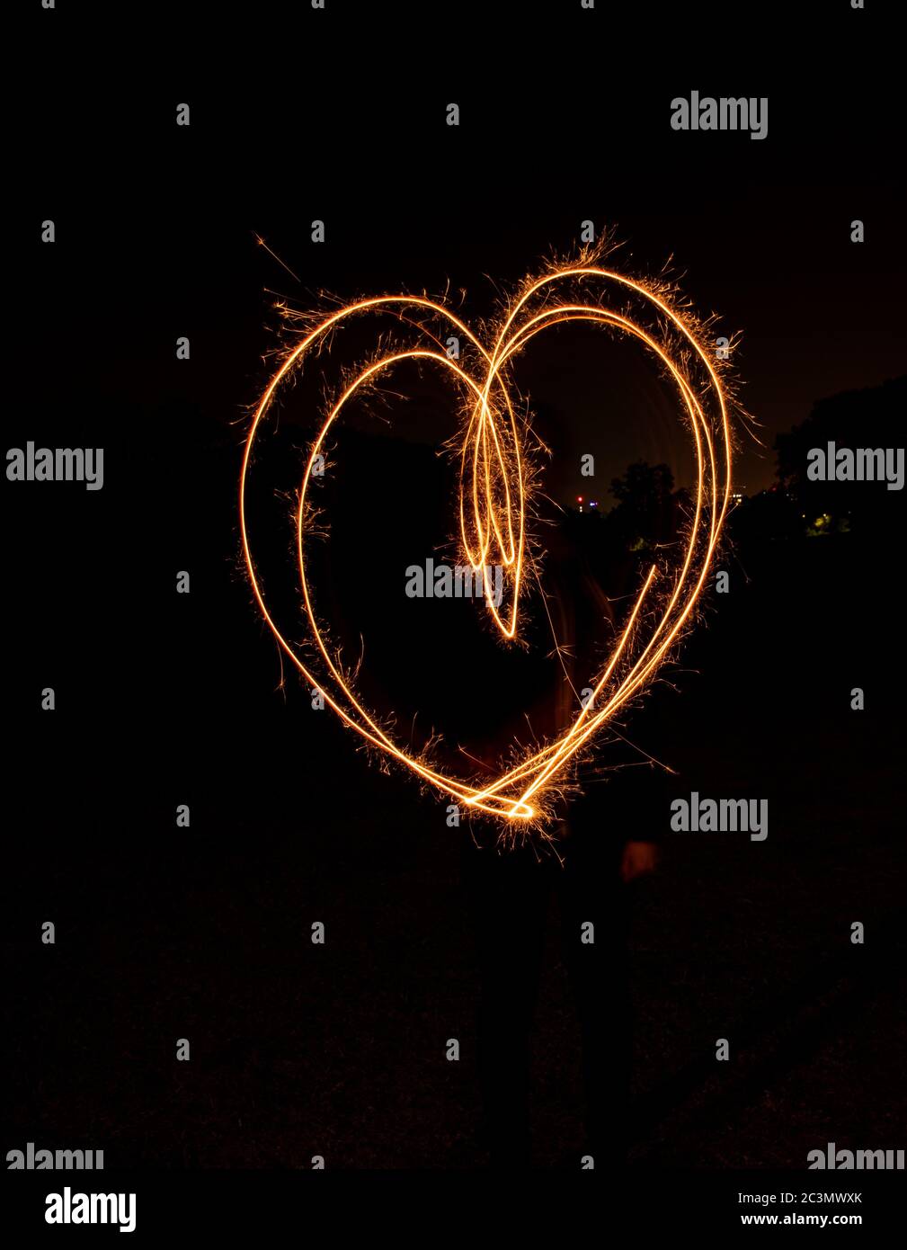 Vertical sparkler painting of the shape of a heart isolated on a black ...