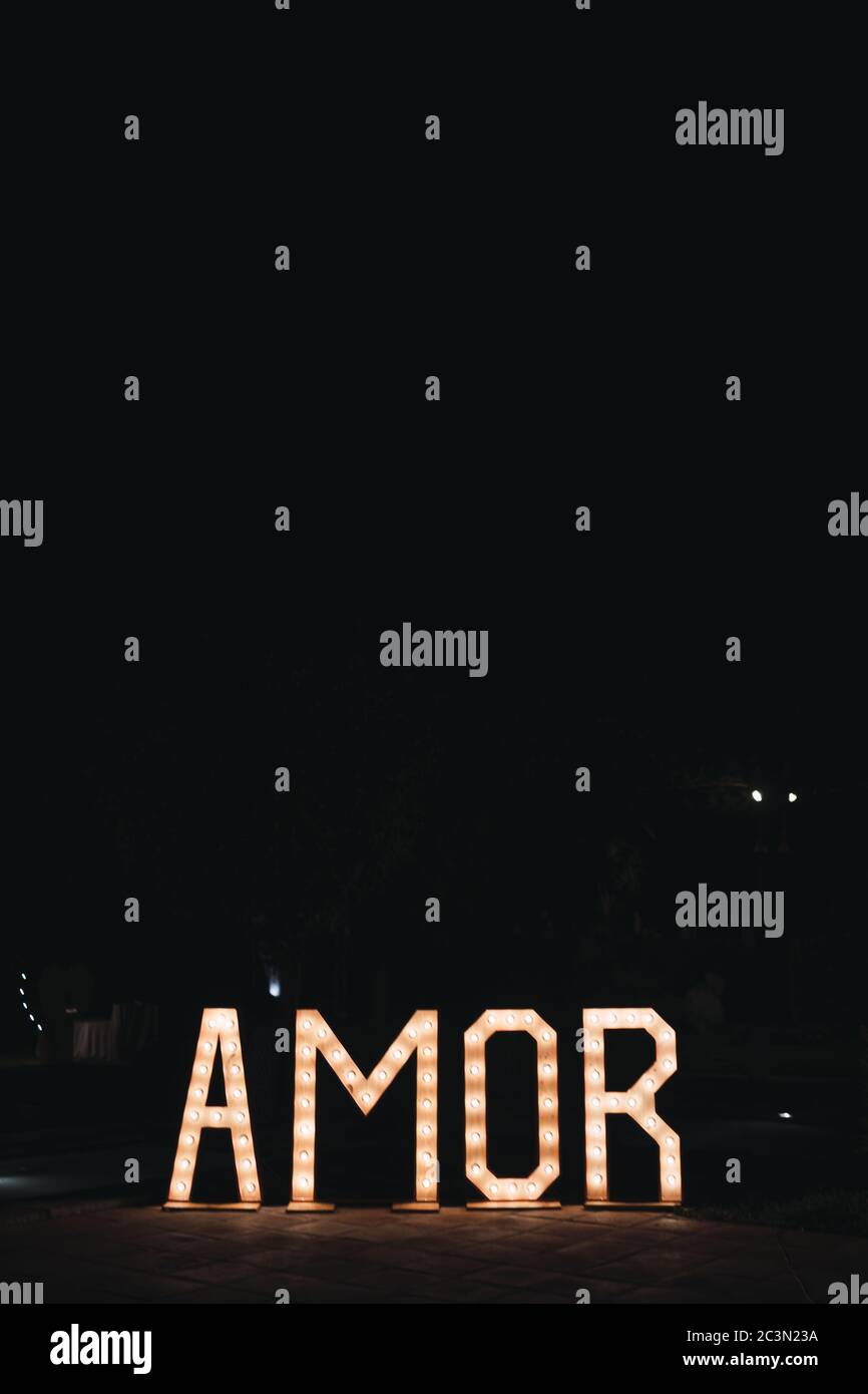 Vertical shot of letters-shaped lights completing "AMOR" text together ...