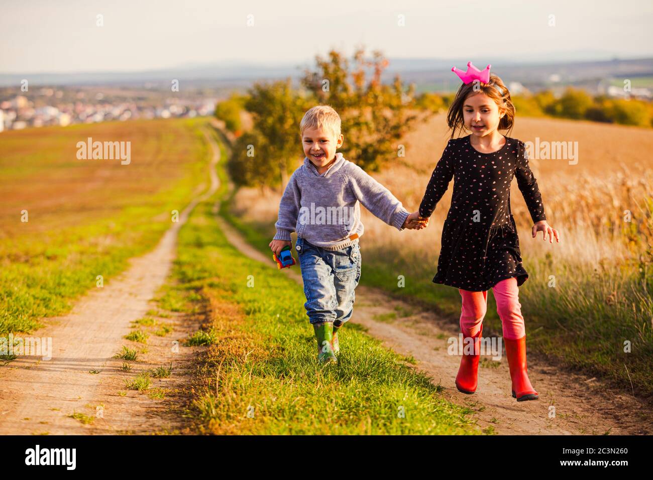 Brother and sister walking on dirt road out of town Stock Photo - Alamy
