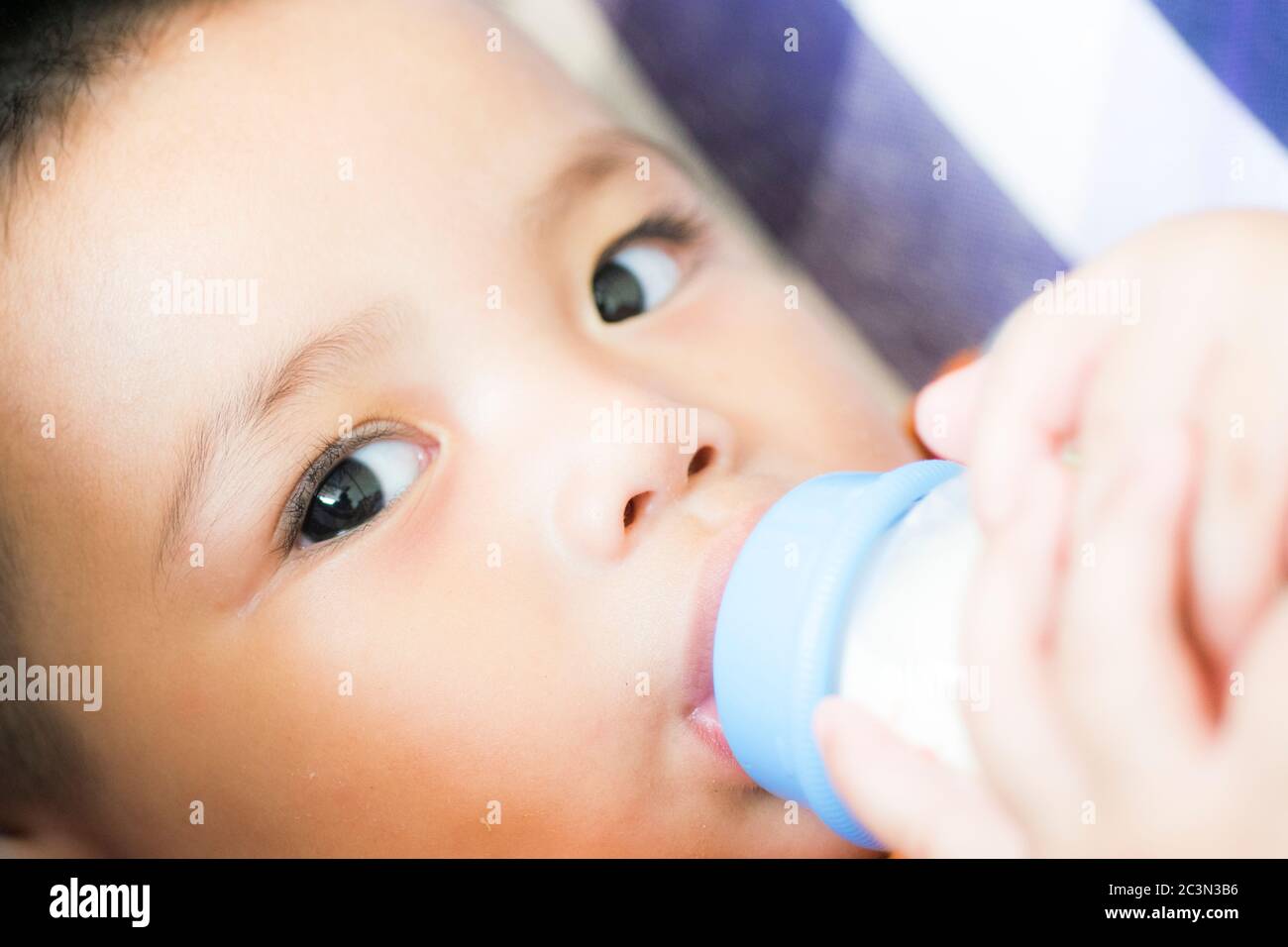An asian male baby - boy is drinking milk using milk bottle in the ...