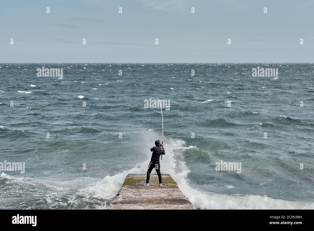 A young man fishing in the Irish sea off Dun Laoghaire pier, Dublin ...