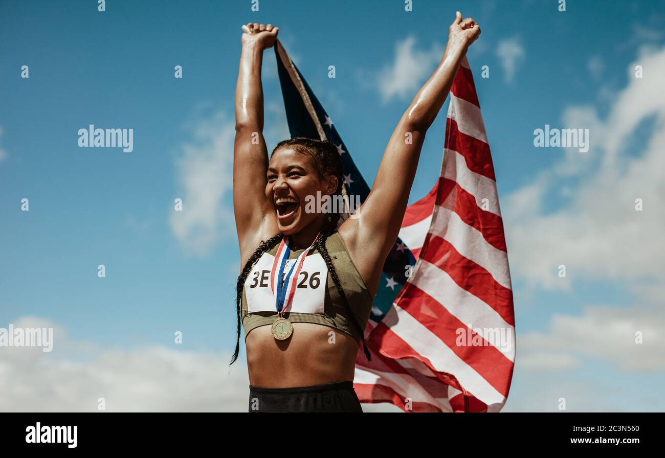 Female runner with a medal celebrating victory holding american flag ...