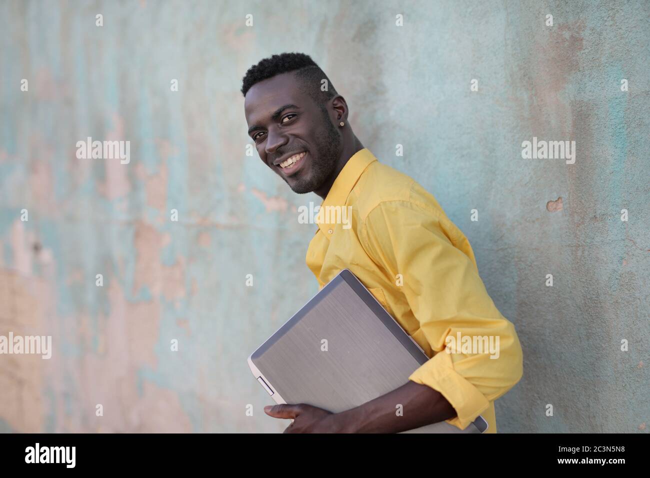 Black man with a case in his hands smiling behind a wall Stock Photo ...