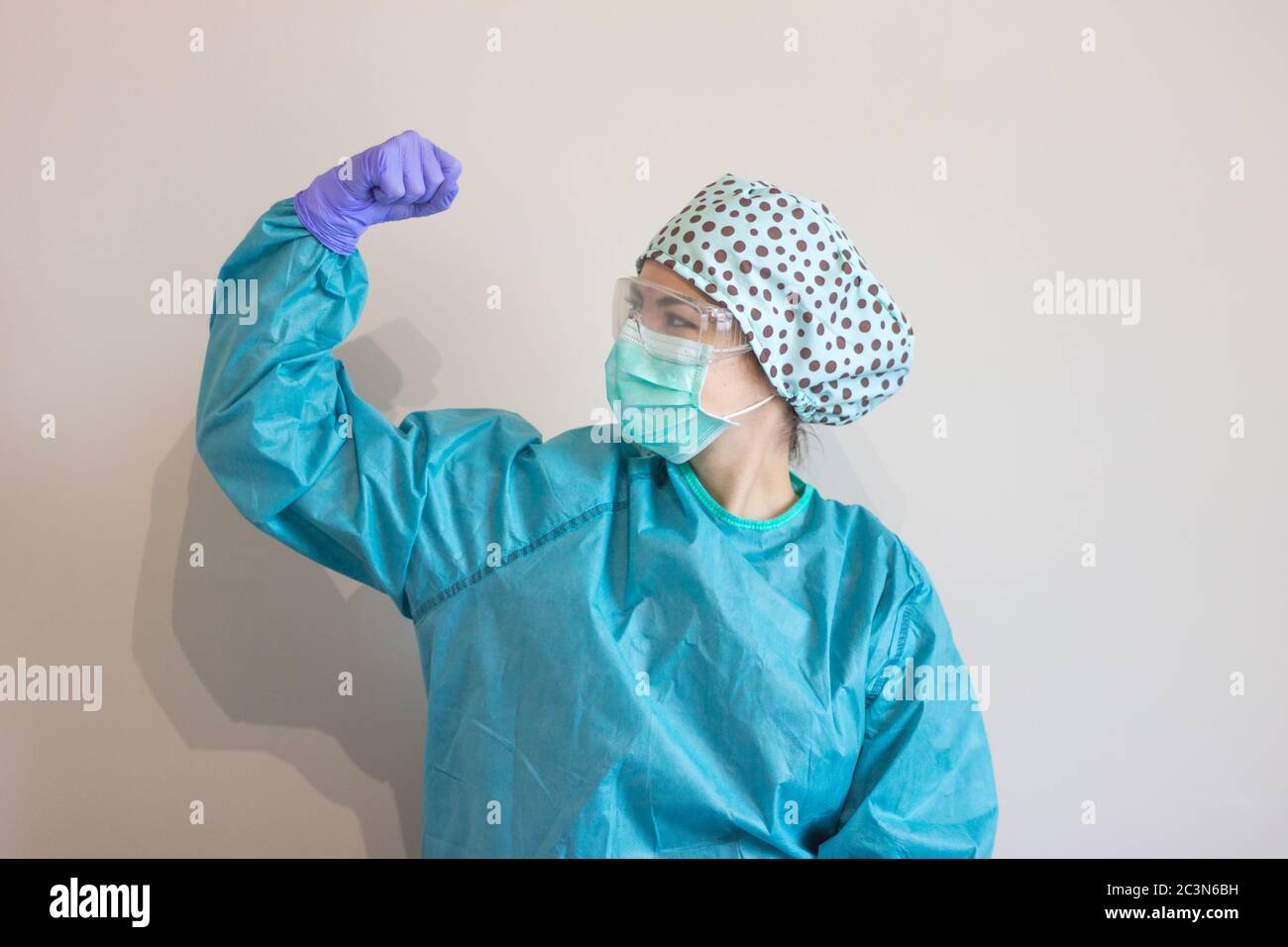 Nurse with medical face mask and gown showing muscles emphasizing the ...