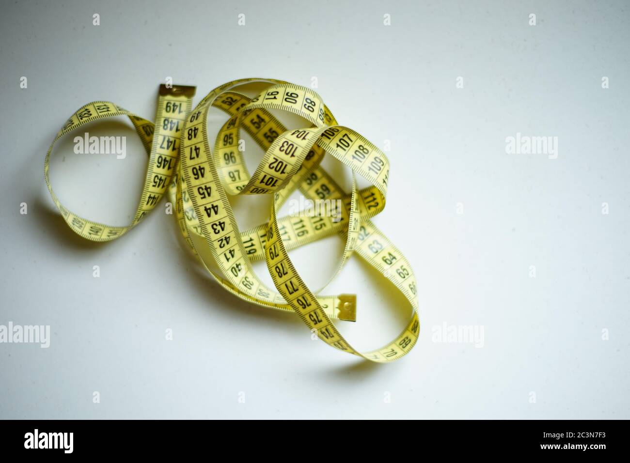 Yellow measuring tape on the white table, top view Stock Photo - Alamy
