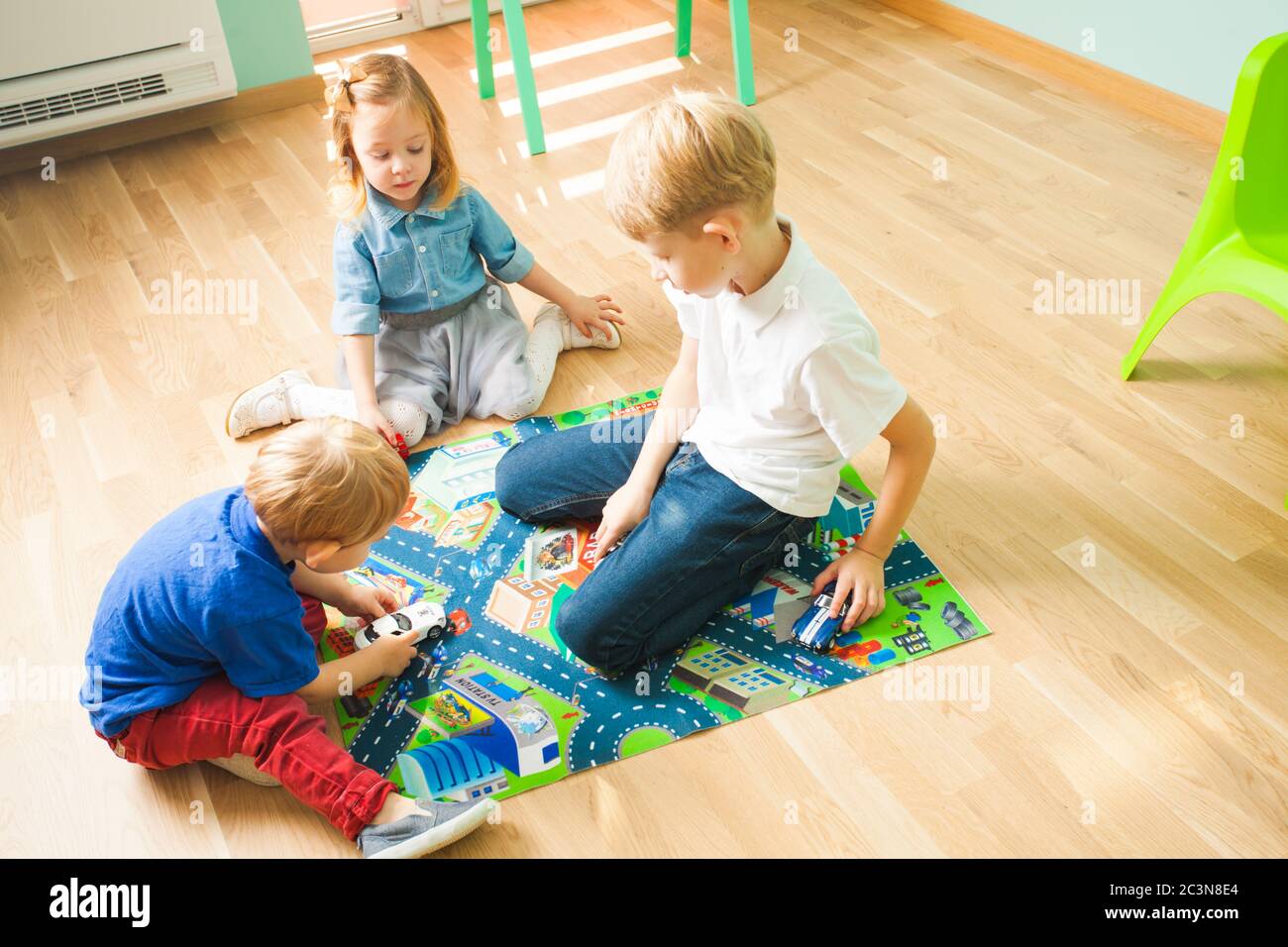 Children playing with cars on a road themed carpet. Kids at home or ...