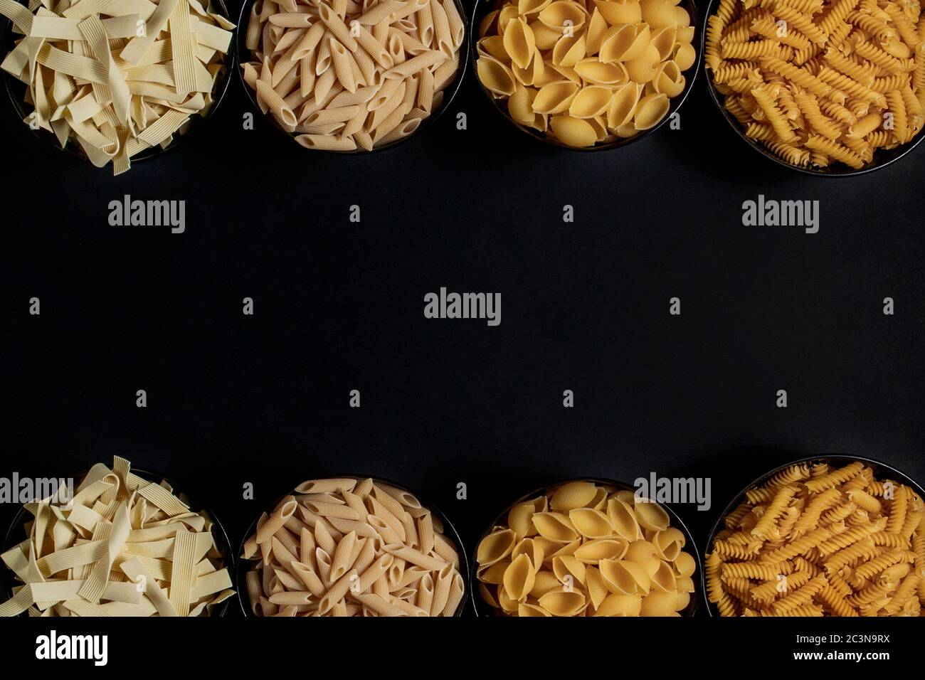 Different types of dry pasta on the plate and in bowls on black ...