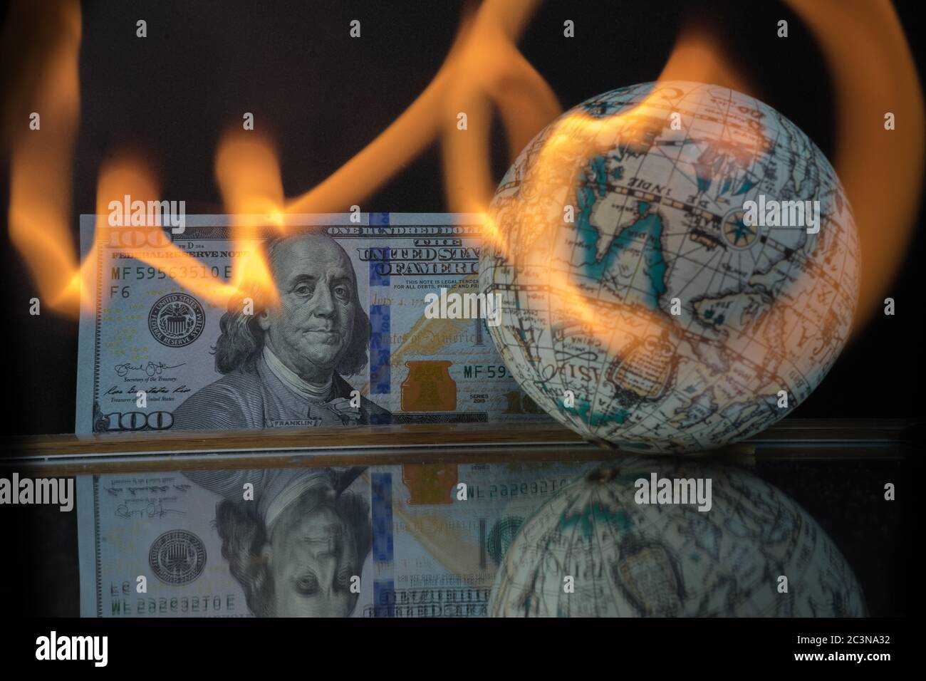 Small globe next to the dollar sign burning with fire Stock Photo - Alamy