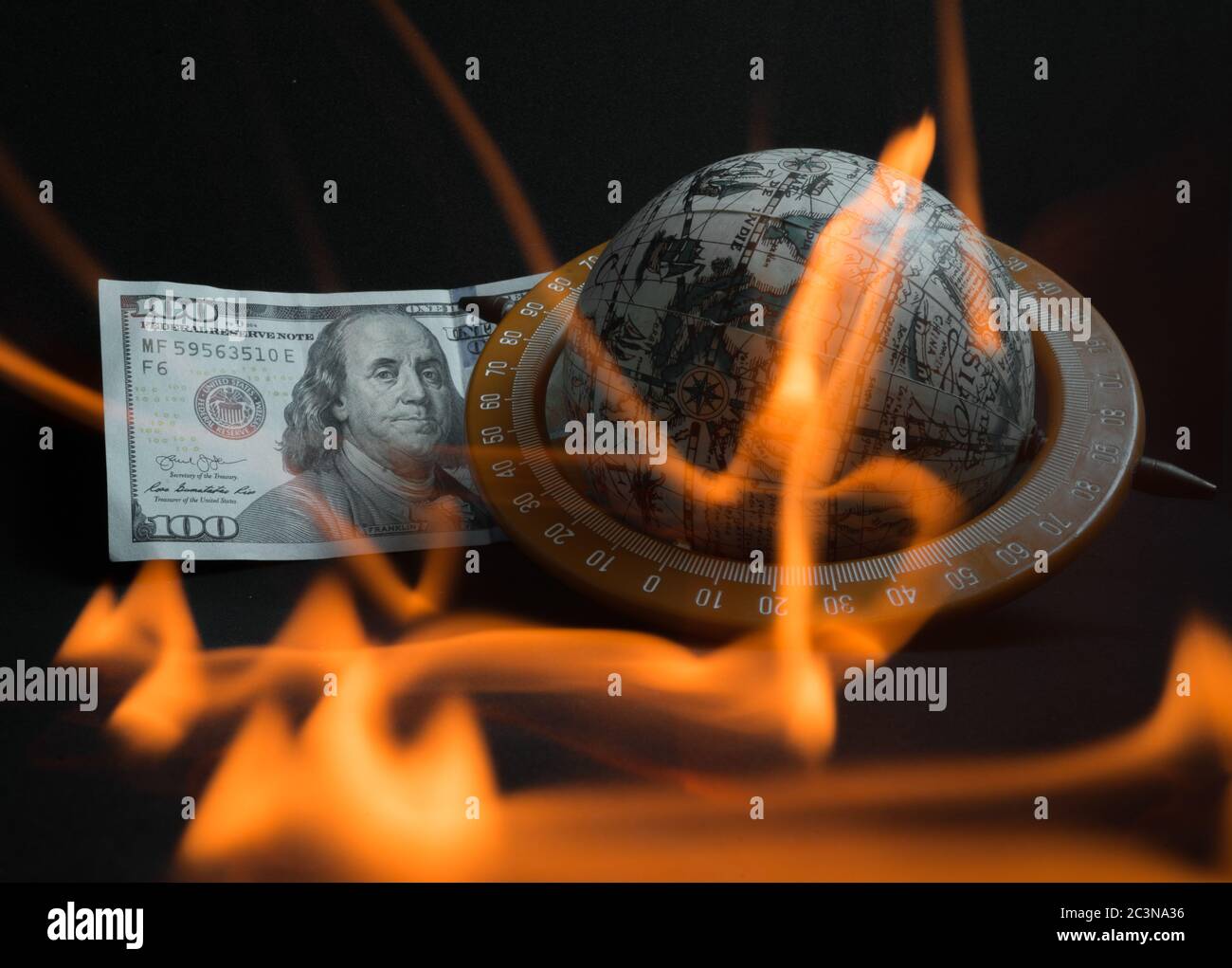Small globe next to the dollar sign burning with fire Stock Photo - Alamy