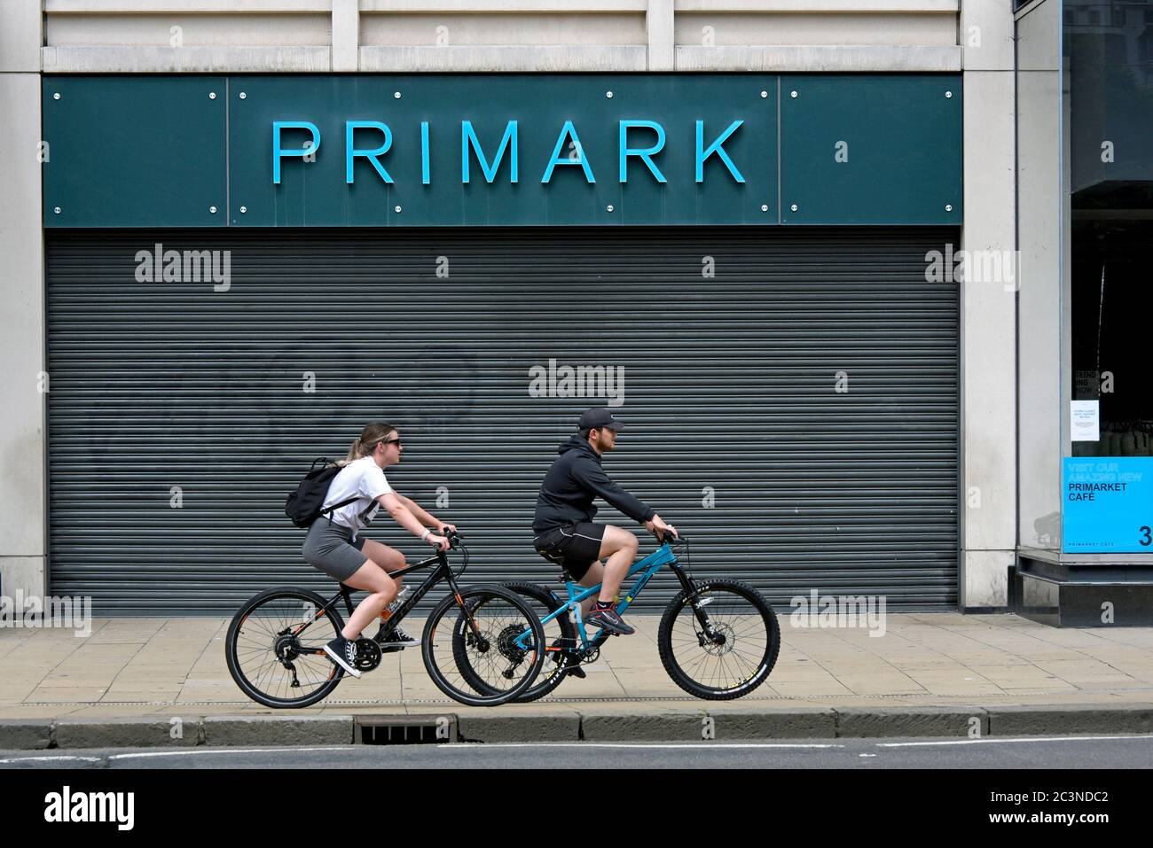 Two cyclists ride by the shuttered door of the Primark store on Princes ...