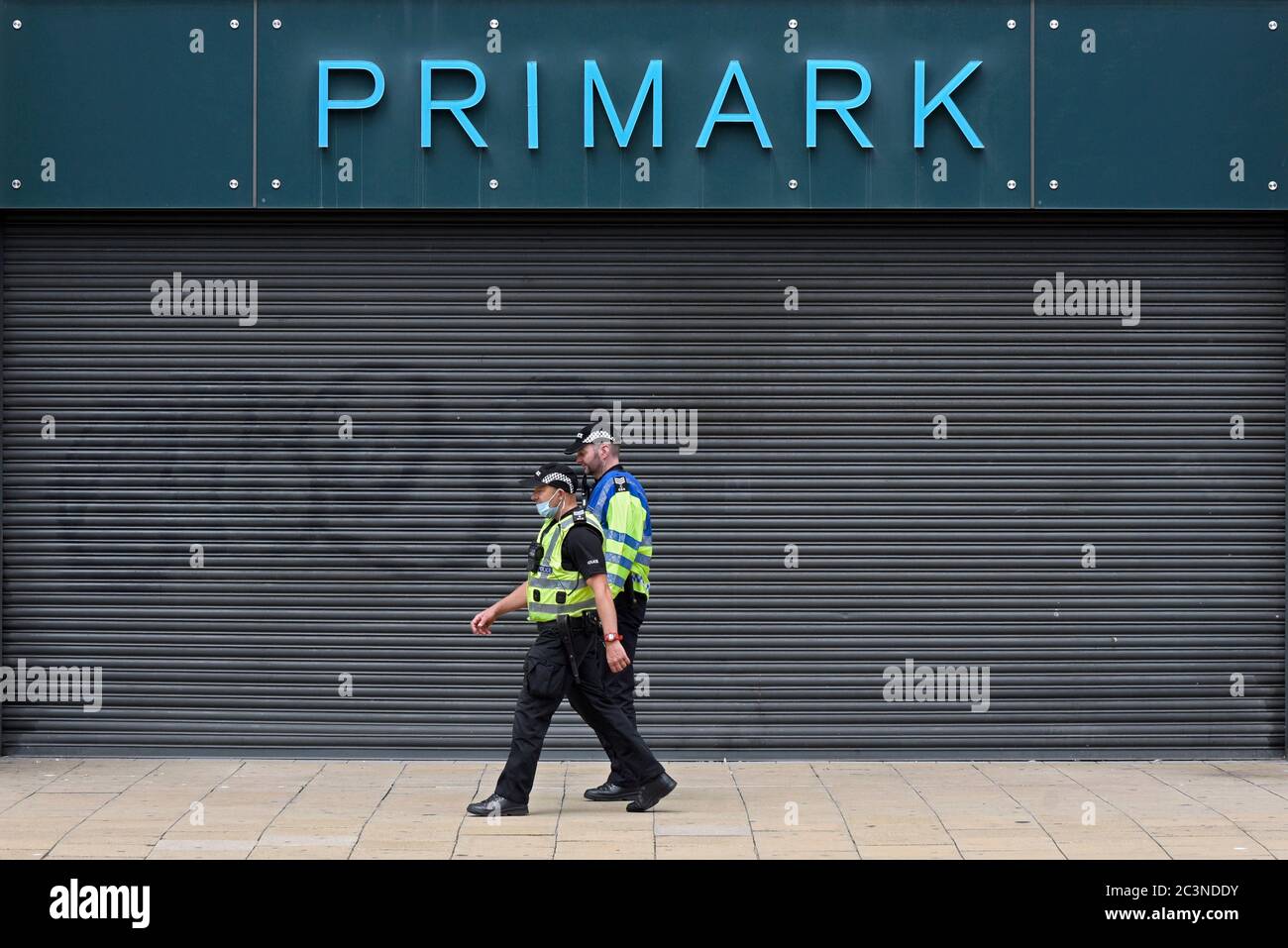Police officers walk by the shuttered door of the Primark store on ...