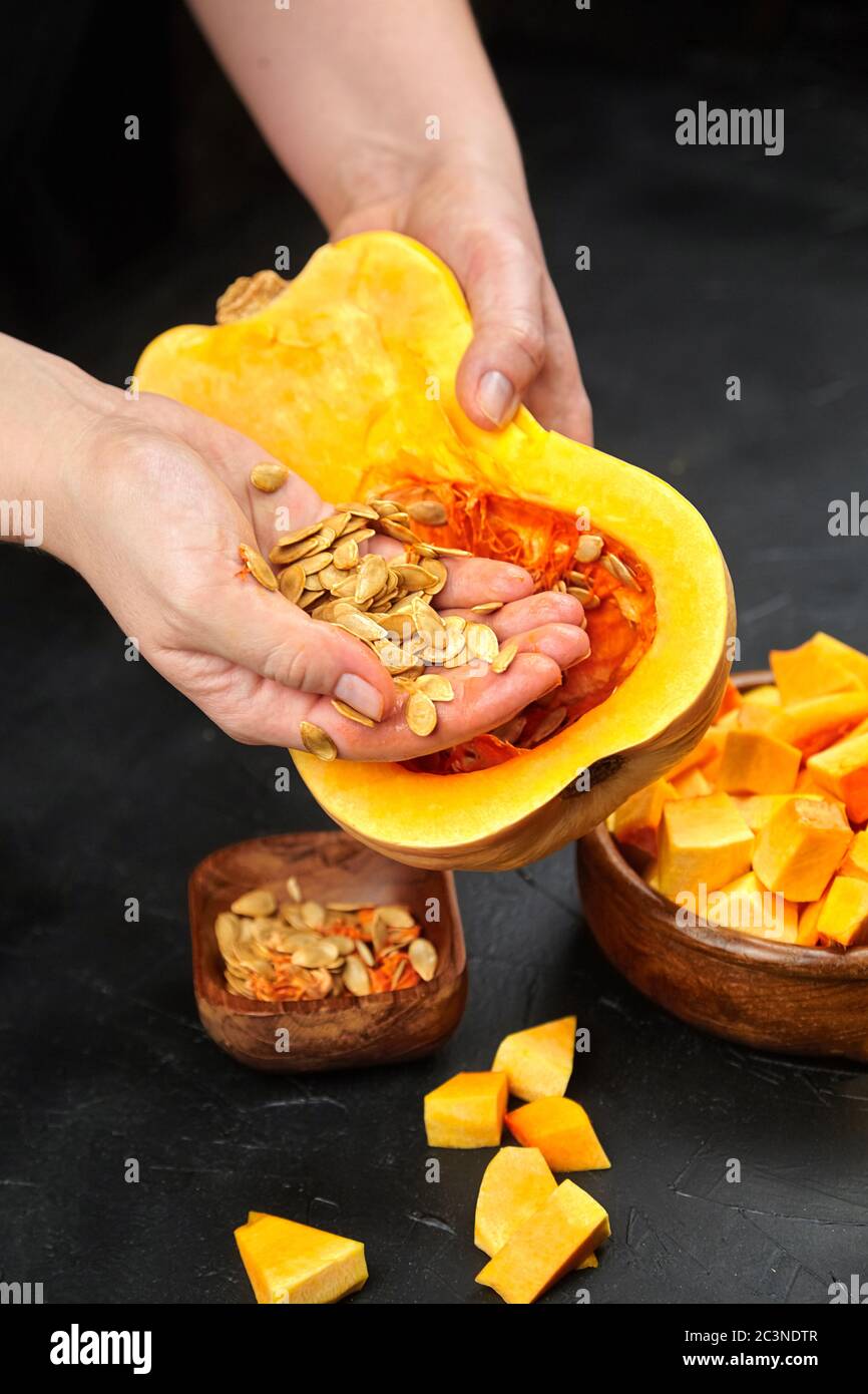 Woman removing pumpkin seeds and stringy fibers. Cooking sweet winter ...