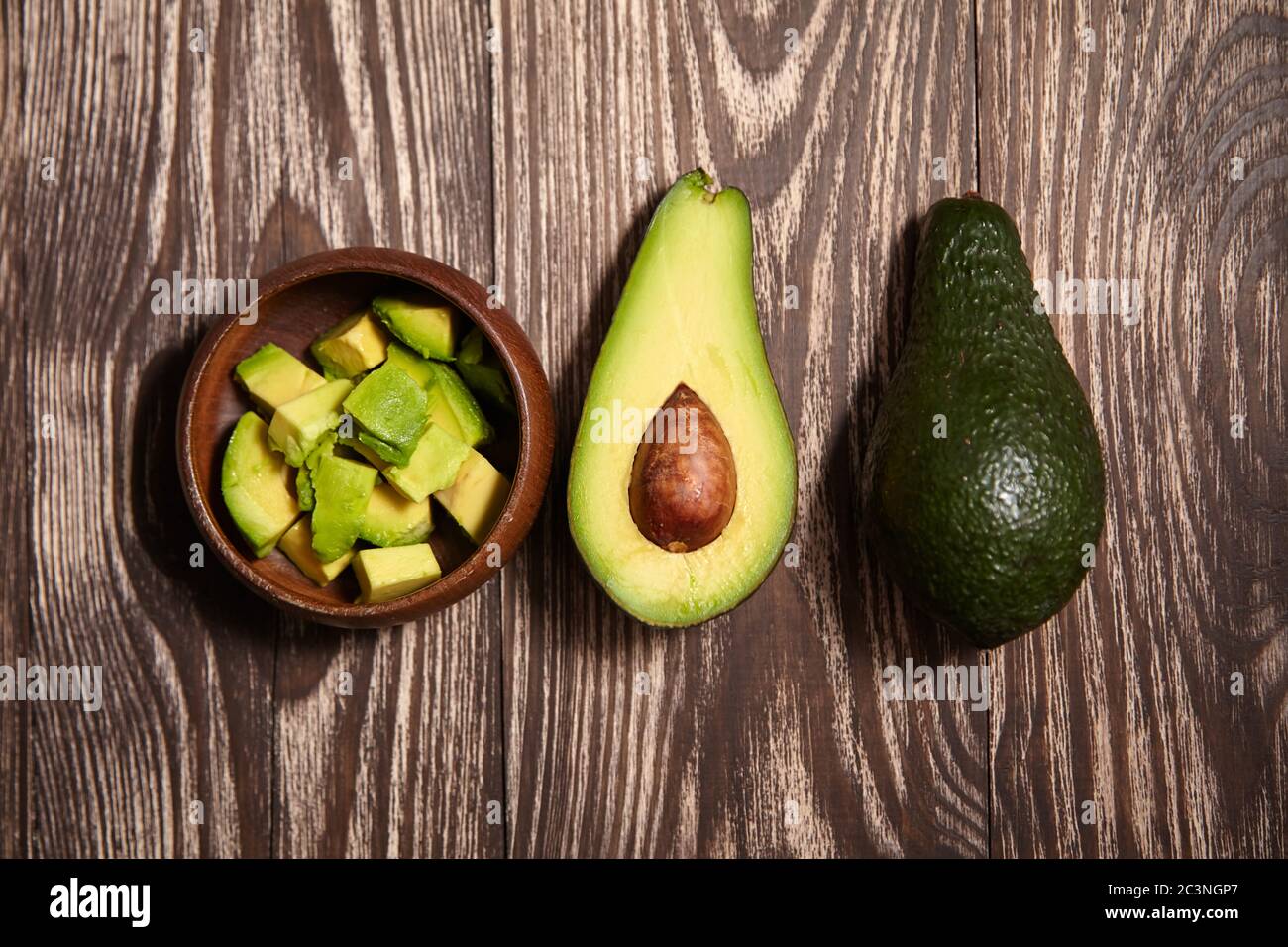 Chopped avocados in a bowl on wooden background. Half avocado with pulp ...