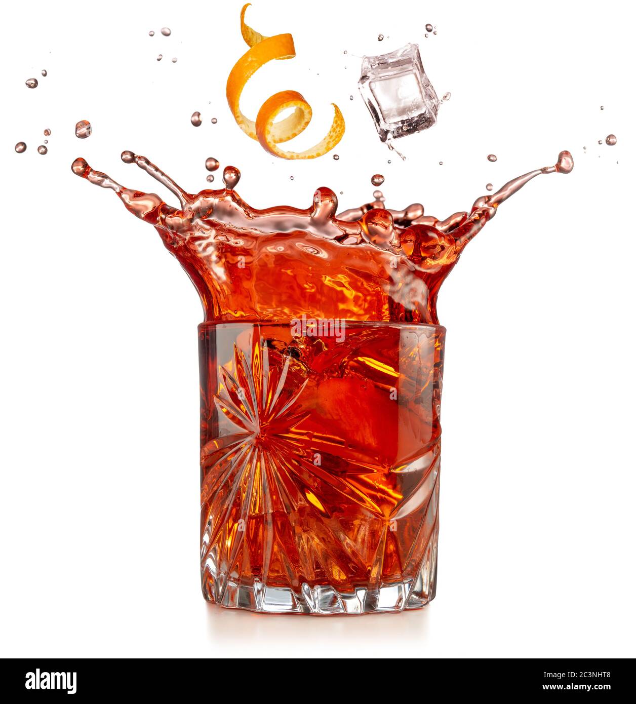 orange zest and ice falling into splashing negroni isolated on white ...