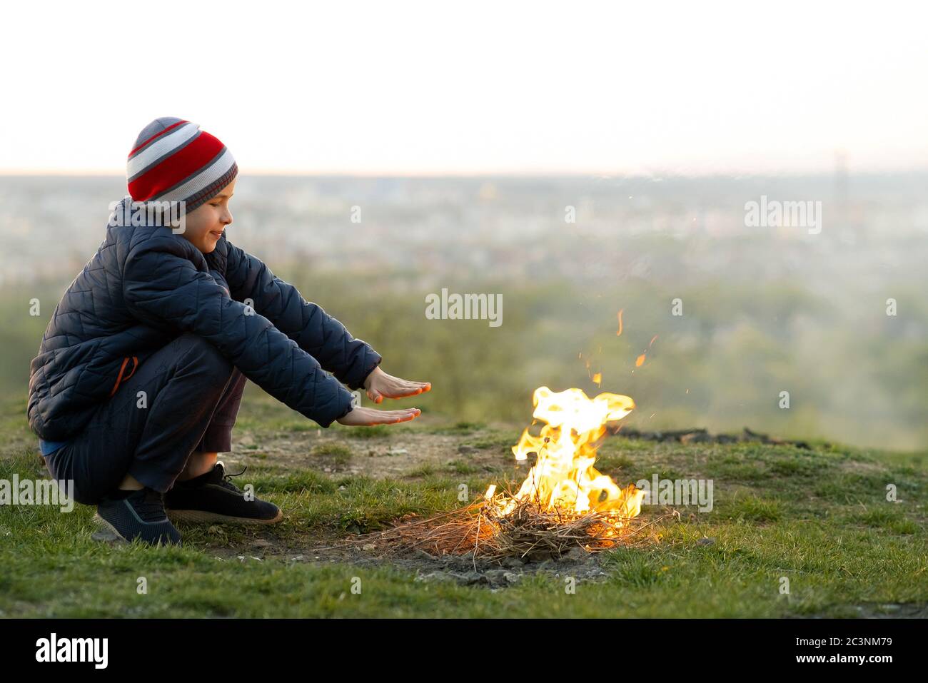 Child boy warming near bonfire outdoors in cold weather Stock Photo - Alamy