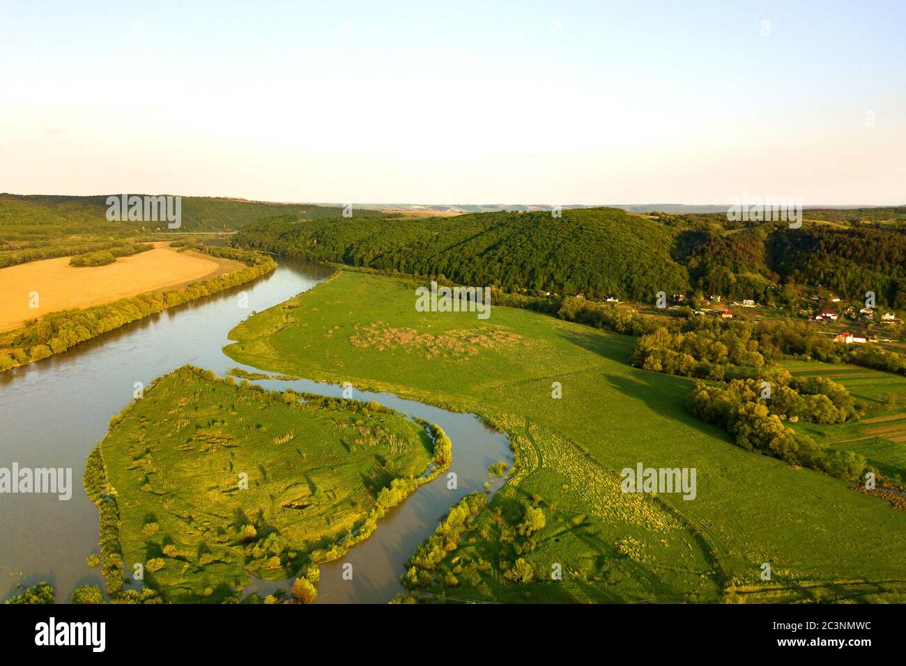 Aerial view of bright river flowing through green meadows in spring ...