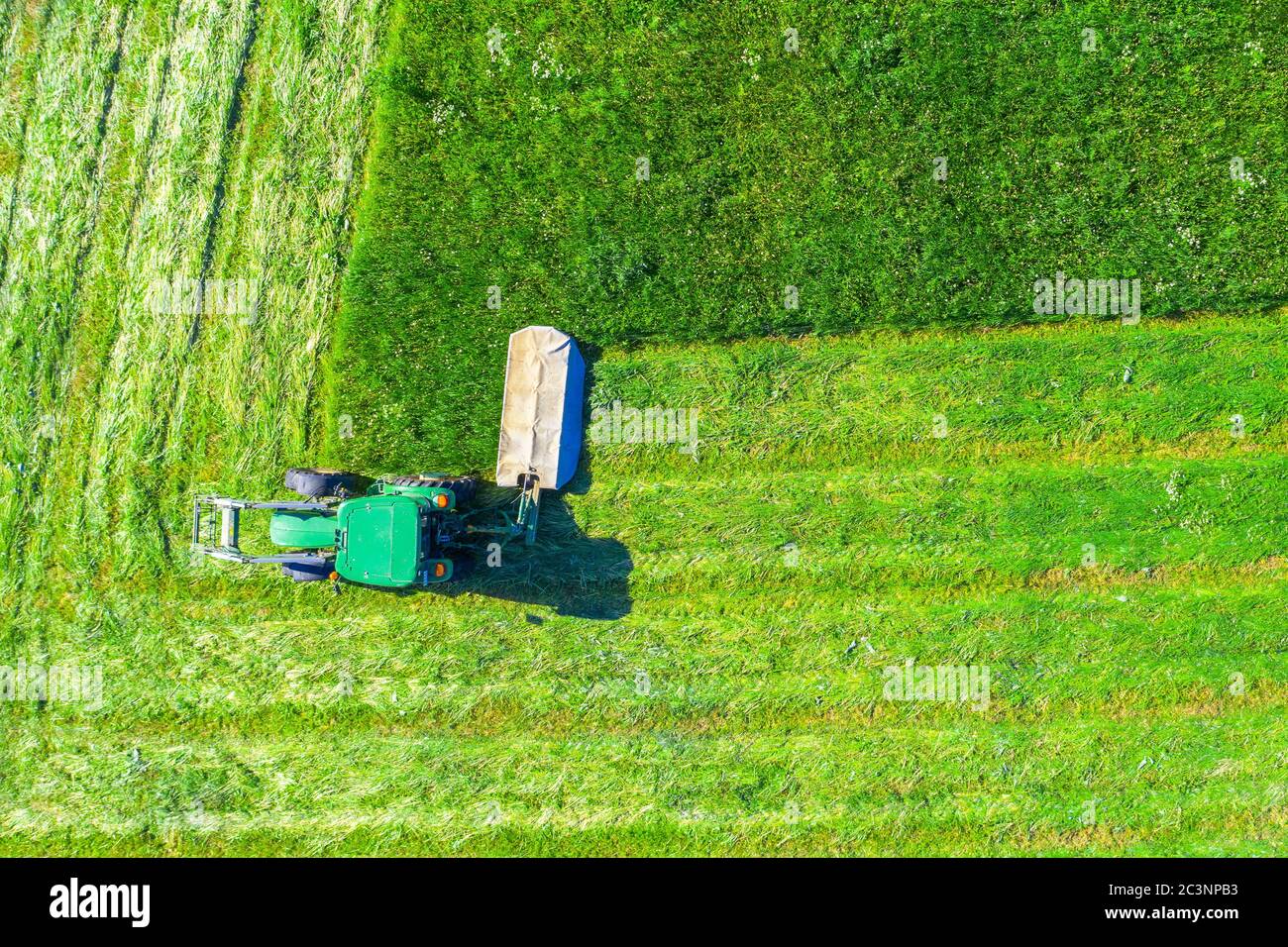 Aerial photo farm scene agricultural tractor mows grass with a mower in ...