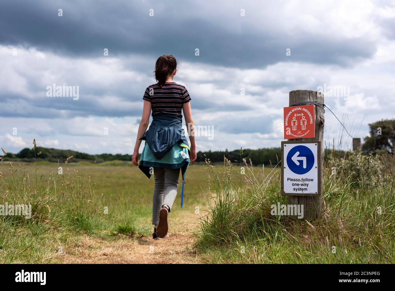 A teenage girl walking on a one way route in the countryside. Signposts ...