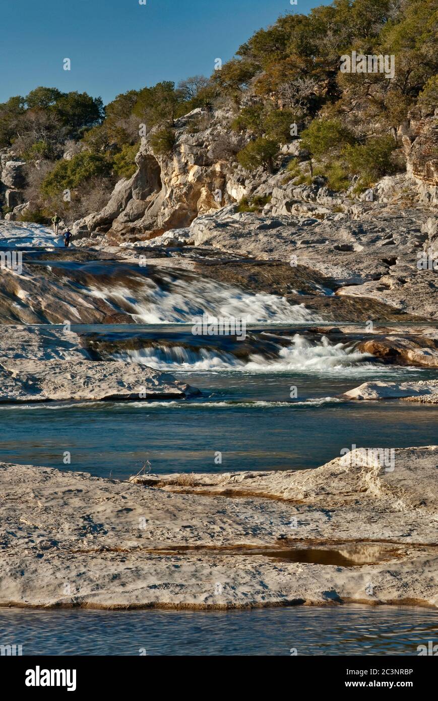 Cascades and pools of Pedernales River with hikers in distance at ...