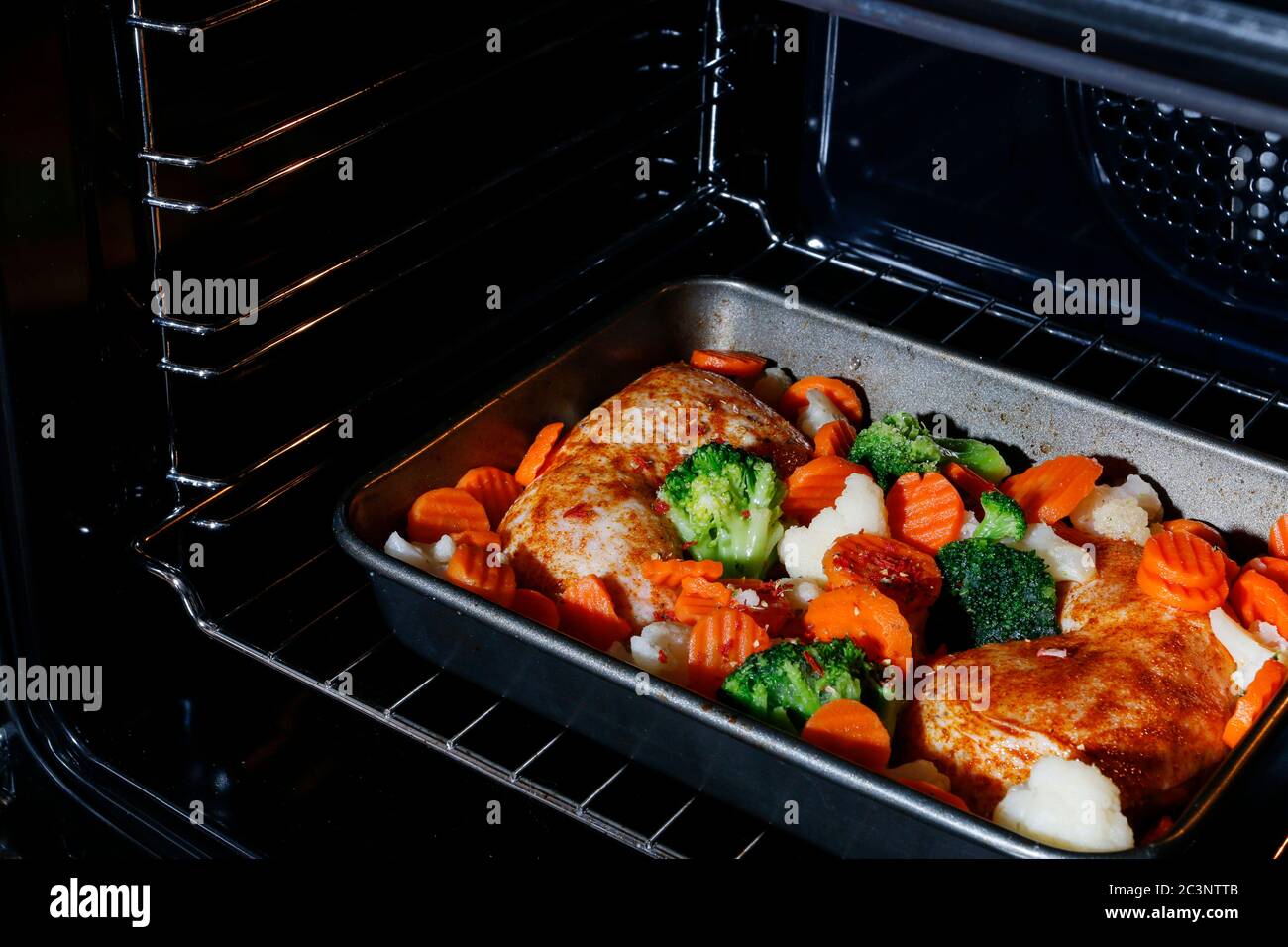 Roasted chicken with vegetables in the oven. Cooking time Stock Photo ...