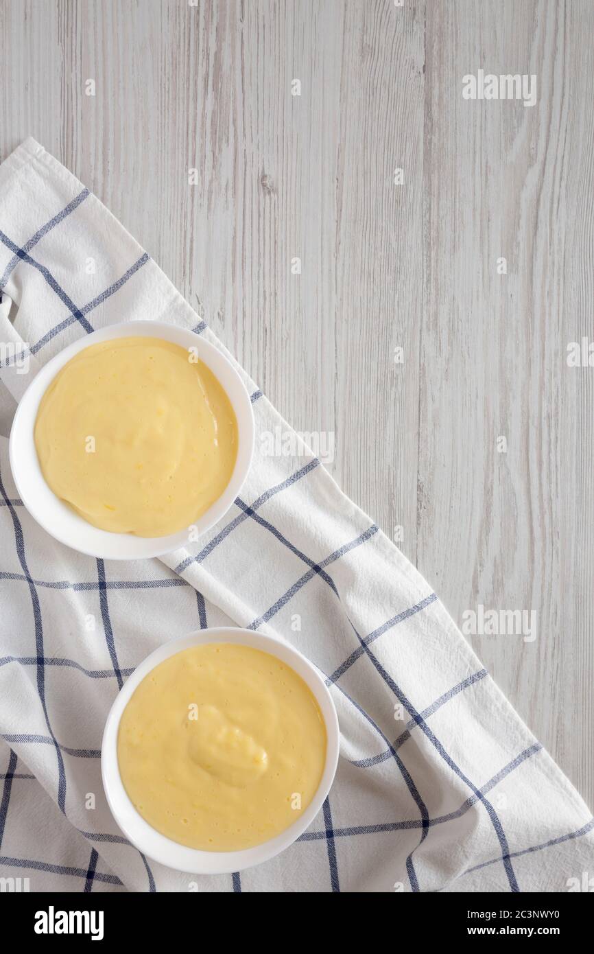 Homemade vanilla custard pudding in white bowls, top view. Flat lay ...