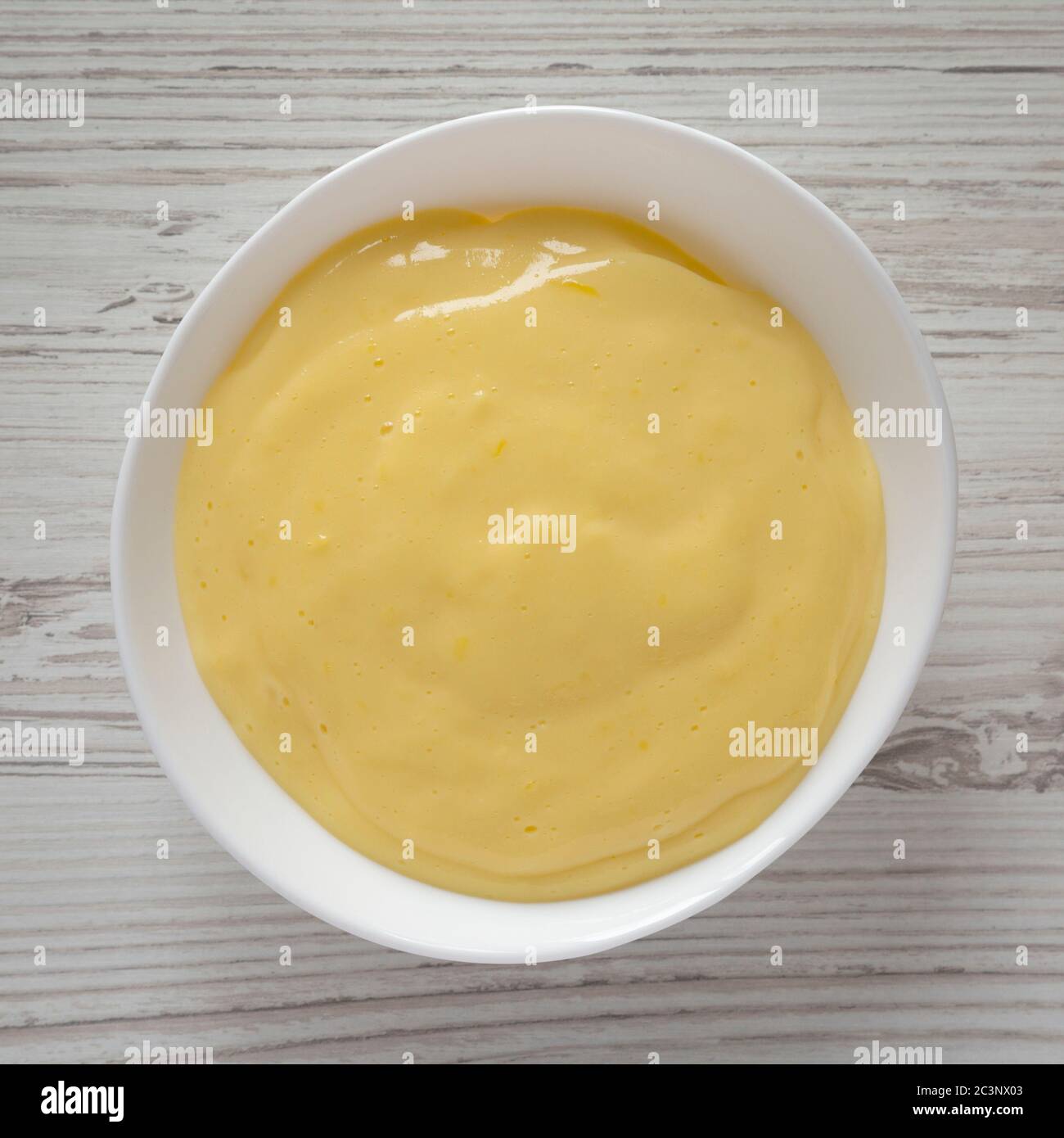 Homemade vanilla custard pudding in a white bowl, overhead view. Flat ...